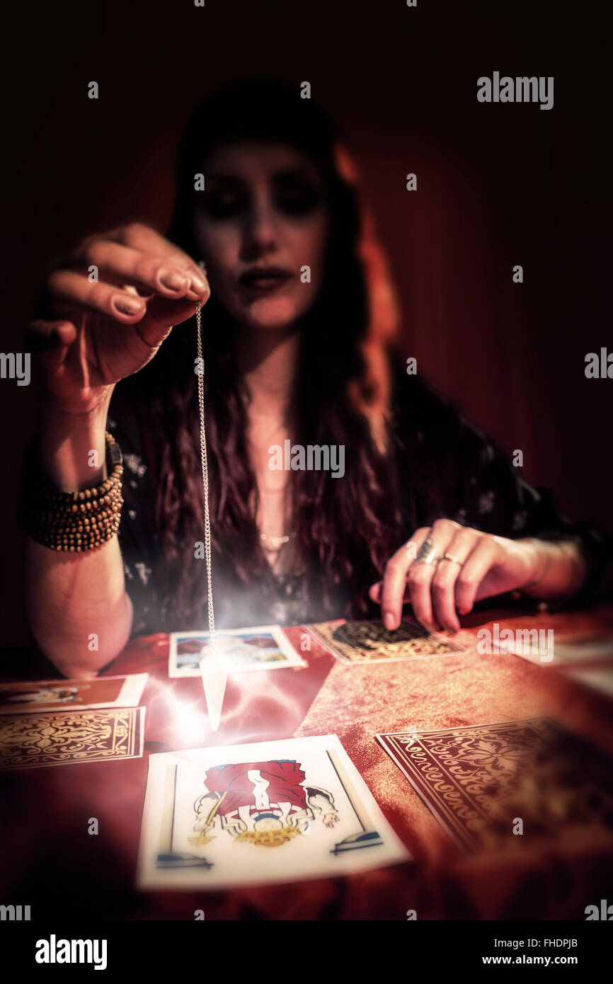Composite image of female fortune teller using pendulum Stock Photo - Alamy