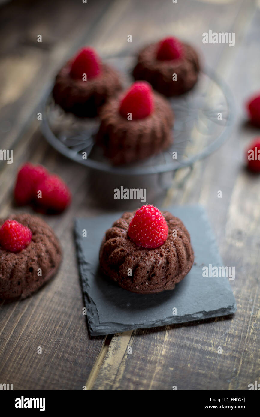 Mini cakes with raspberries on cooling grid and slate, wood Stock Photo ...