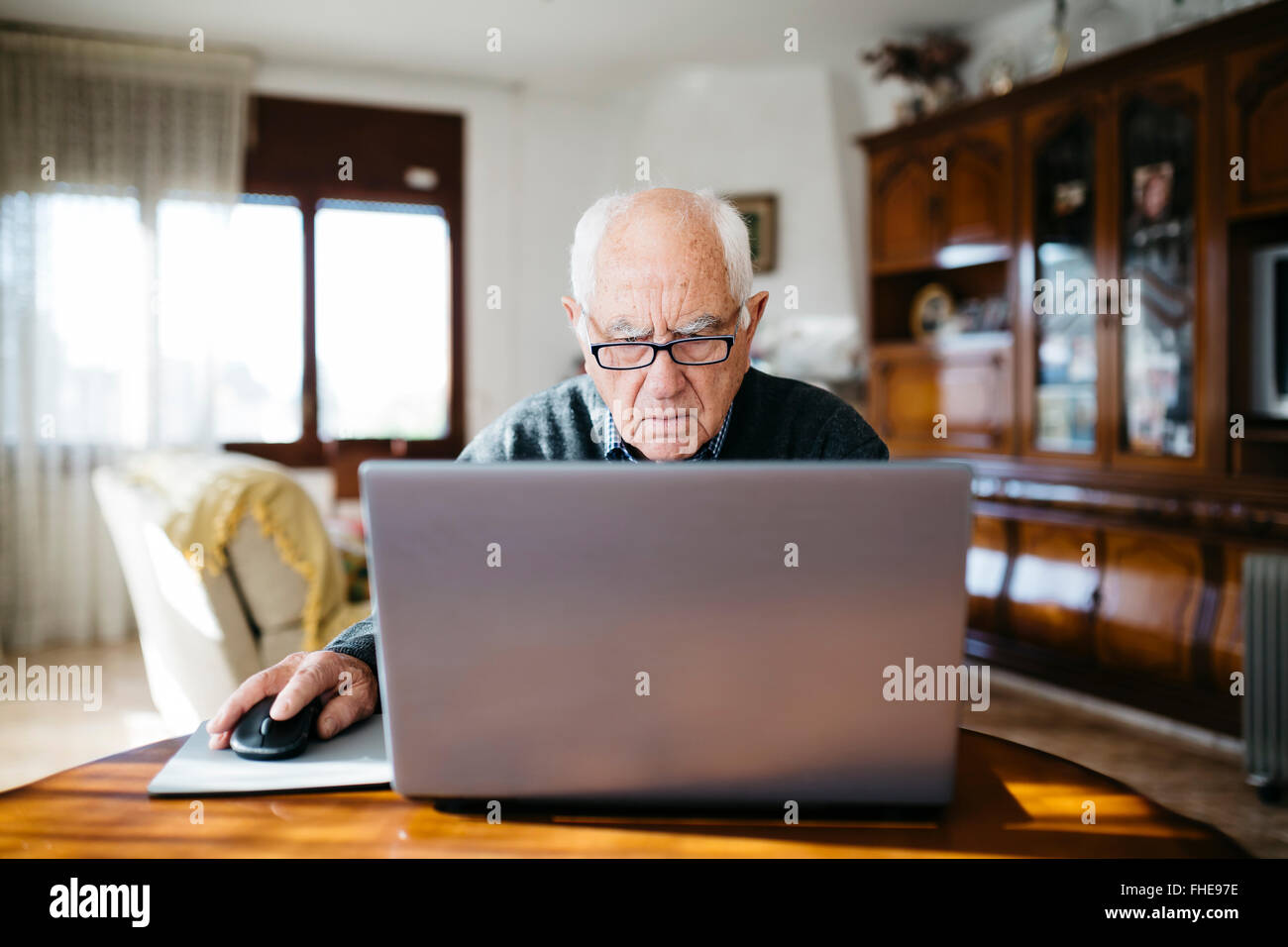 Portrait of serious looking senior man using laptop at home Stock Photo ...