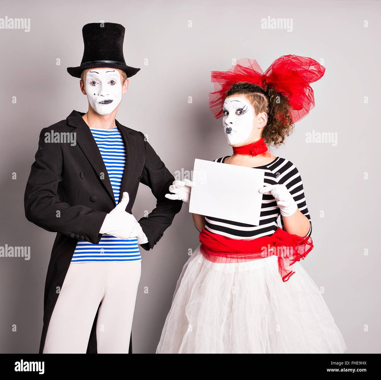 Portrait of happy smiling young actors showing blank signboard, with ...