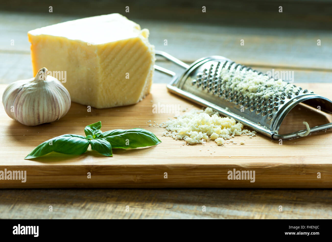 Heap of grated Parmesan on wooden background with leaf of basil, garlic ...