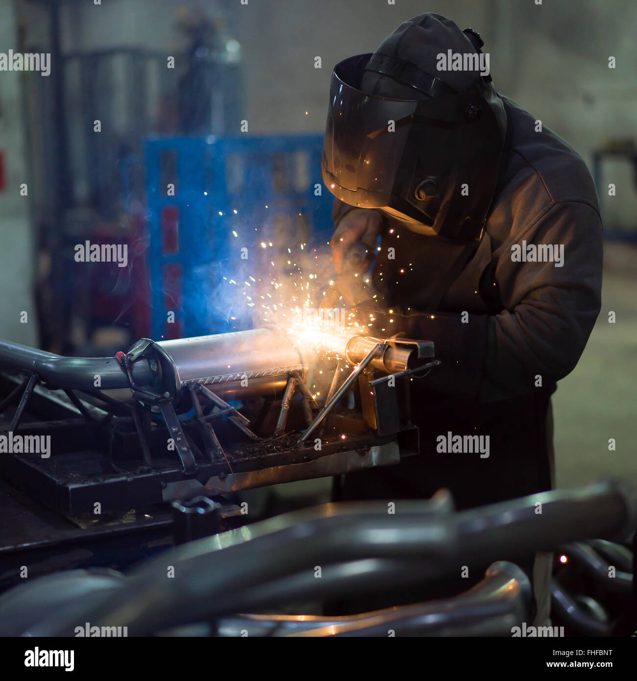 dramatic view of a worker wearing protective gear, welding together ...