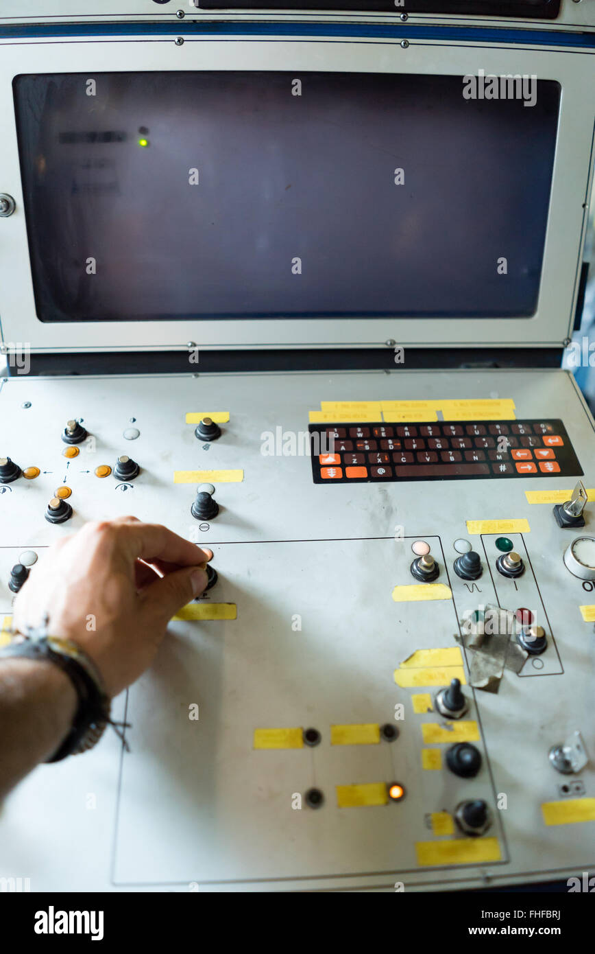 close-up of a man's hand switching knobs on a control panel, with ...