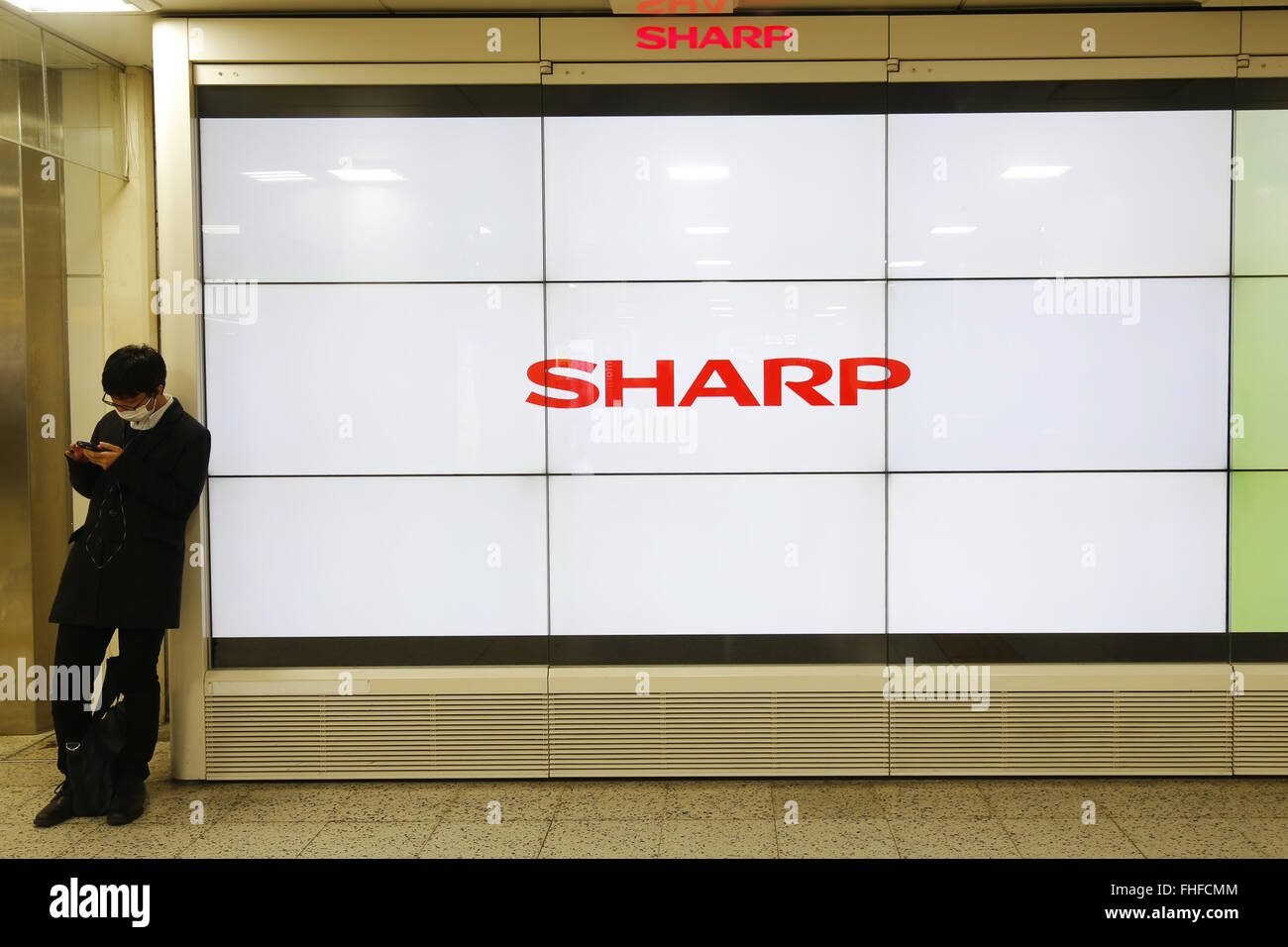 A man stands next to display showing a logo of Sharp Corp in Tokyo ...