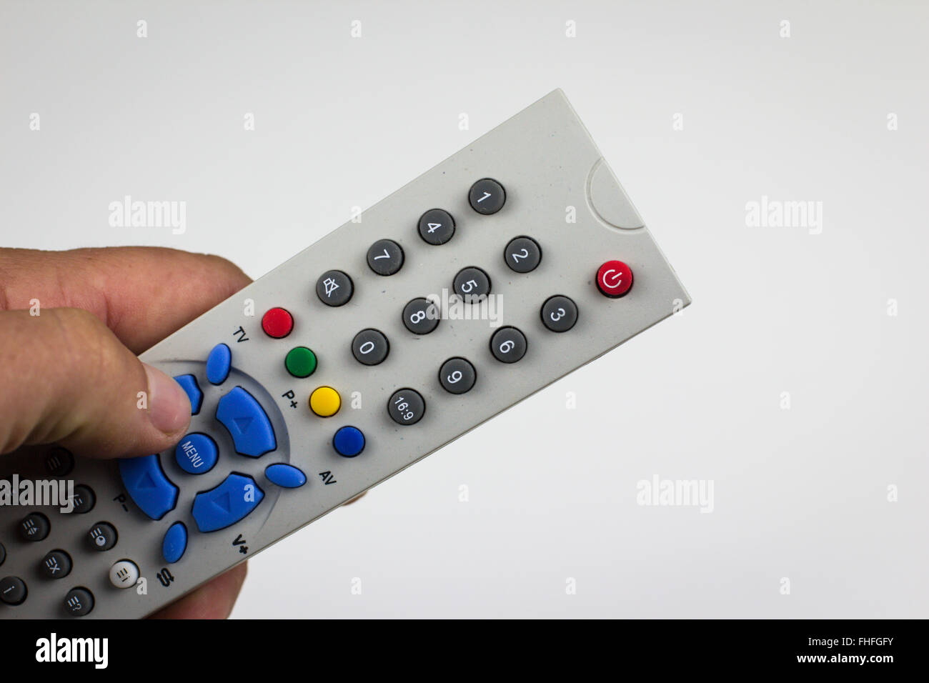 Hand pushes button on dusty, old, simple TV remote over white ...