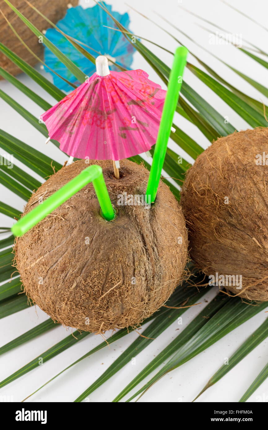 Fresh coconut cocktails with cocktail umbrella placed on coconut leaves ...