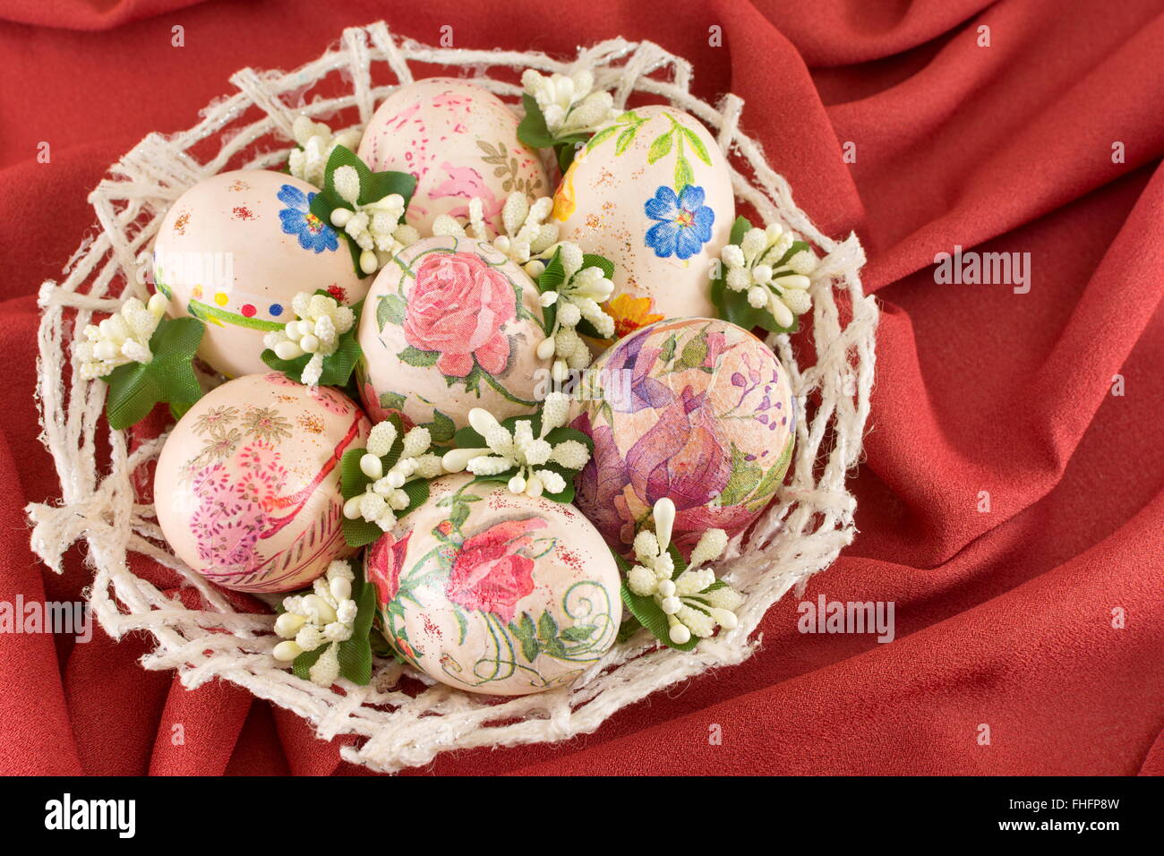 Colorful decoupage decorated Easter eggs in a basket with sof red ...