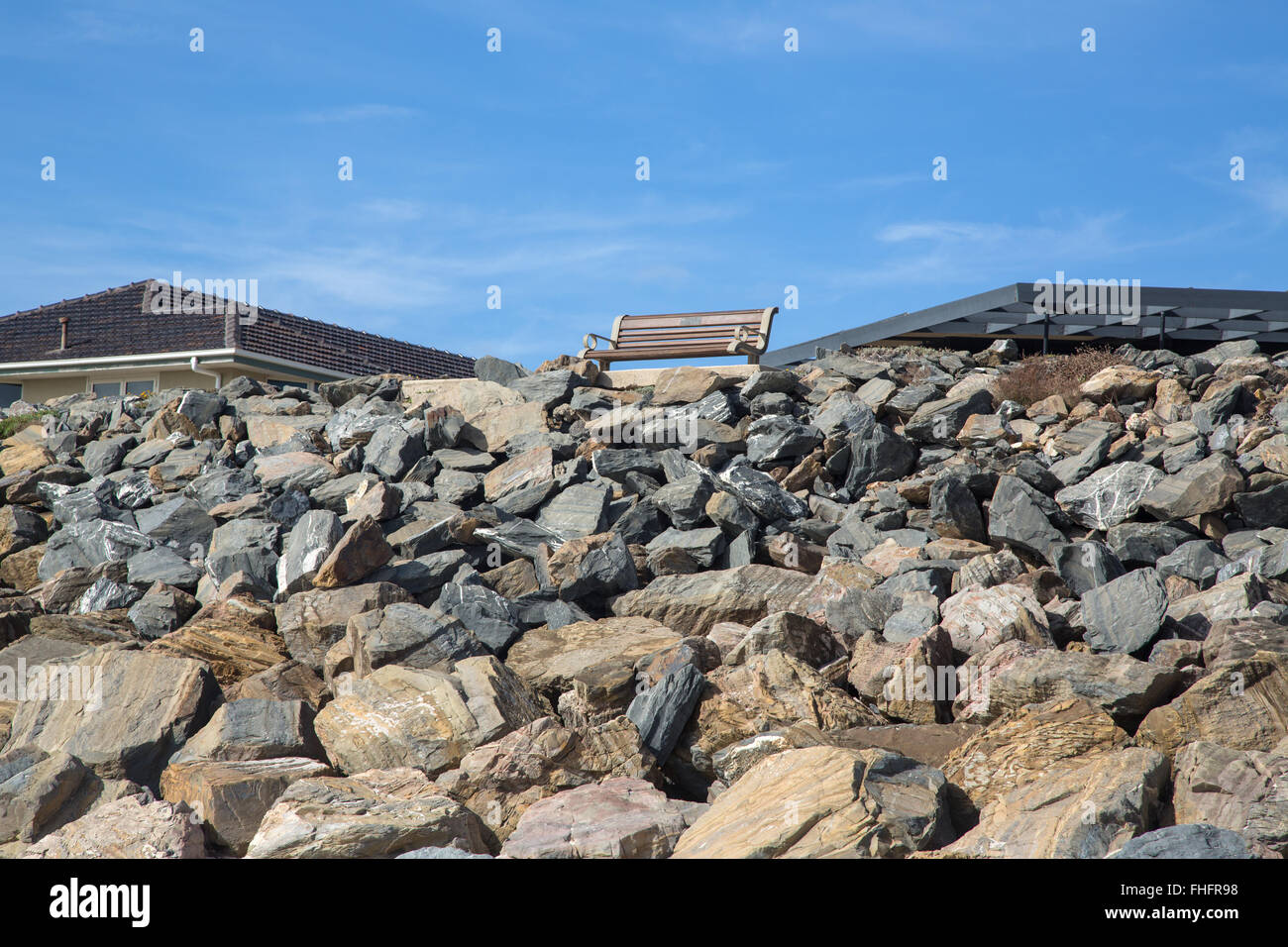 embankment made from rocks with bench atop and roofs of coastline ...
