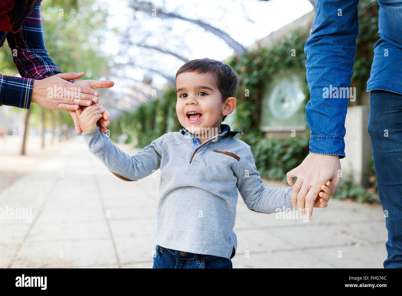 Portrait of happy toddler walking hand in hand with his parents Stock ...