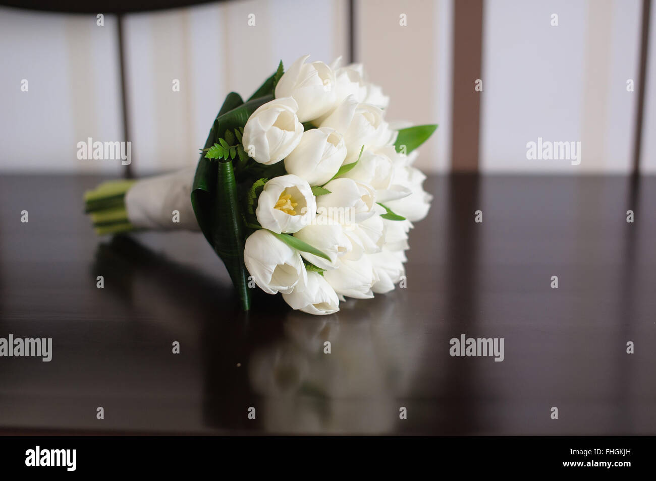 Picture of beautiful white tulips on a reflective table. Side view ...