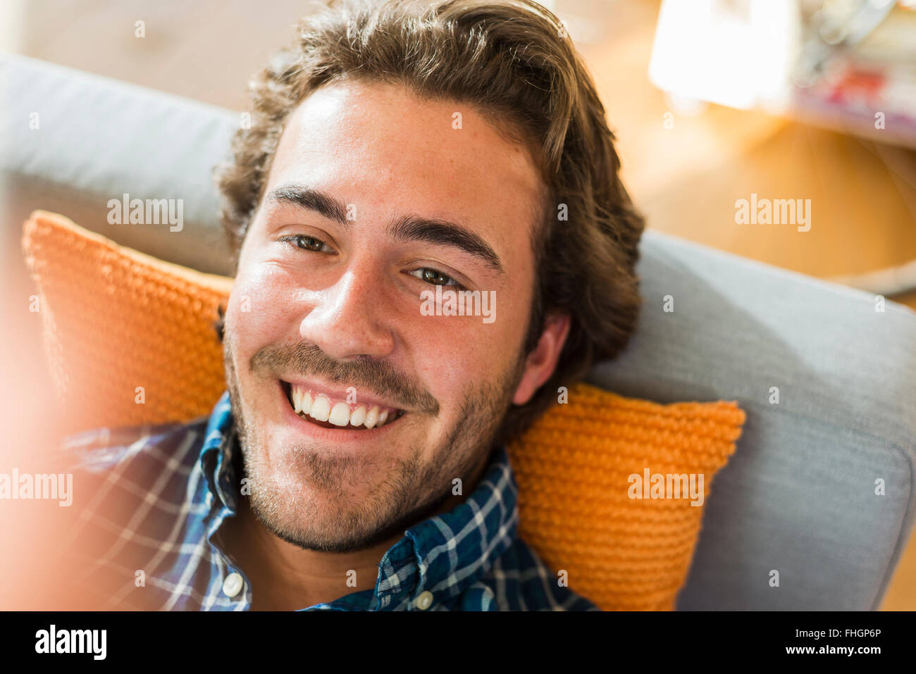 Portrait of smiling young man lying on the couch Stock Photo - Alamy