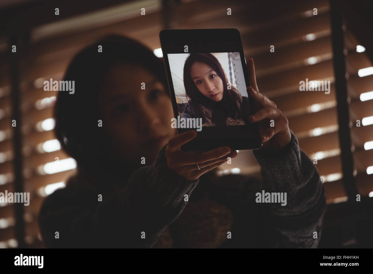 Brunette sitting on the window edge taking selfie Stock Photo - Alamy