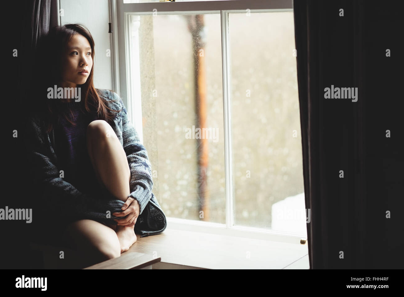 Brunette sitting on the edge of the window Stock Photo - Alamy