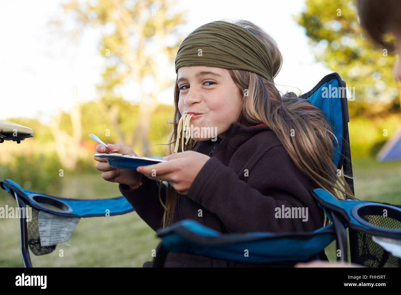 Girl eating spaghetti on a camping ground Stock Photo - Alamy