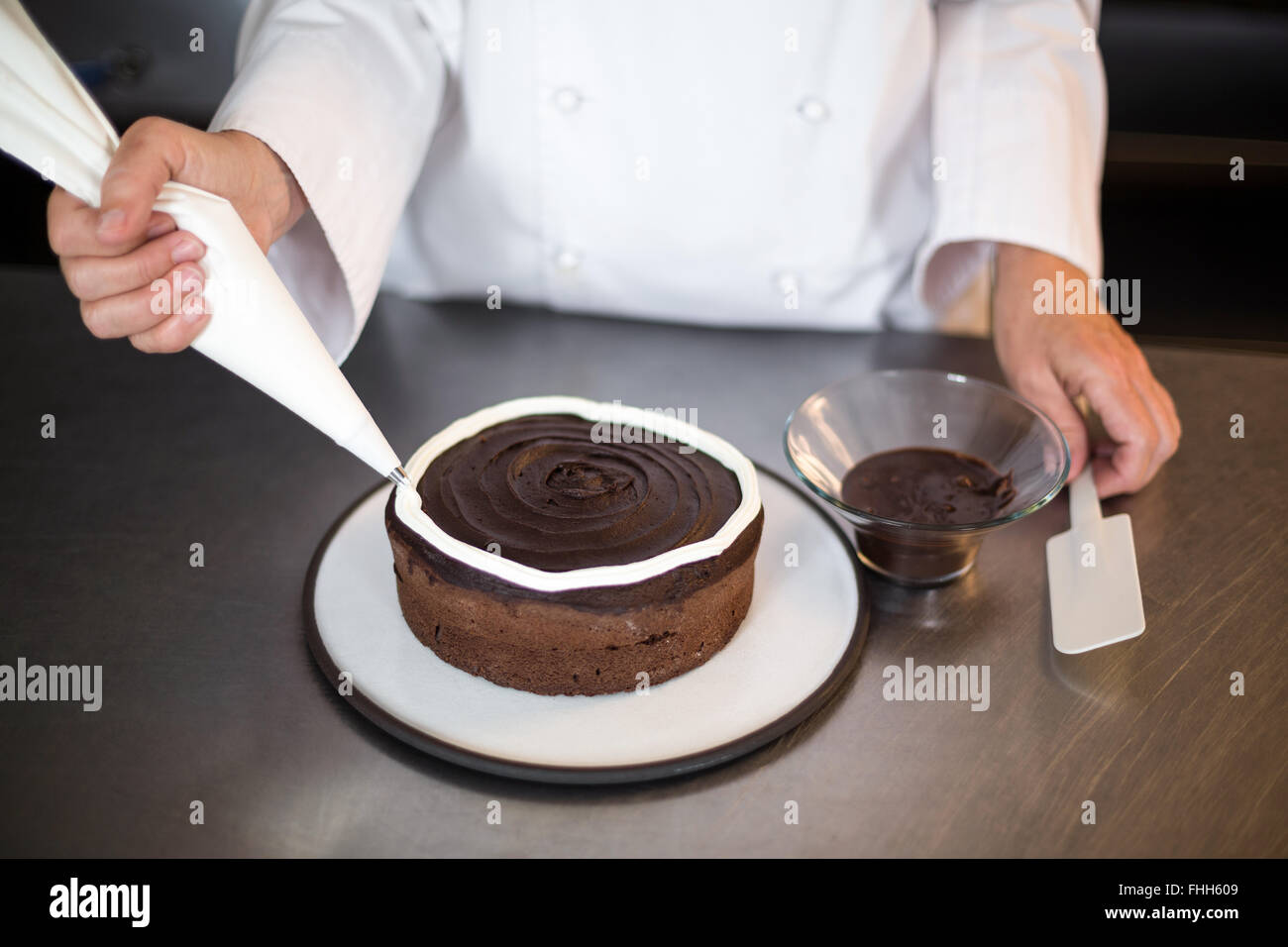 Chef piping icing on cake Stock Photo - Alamy