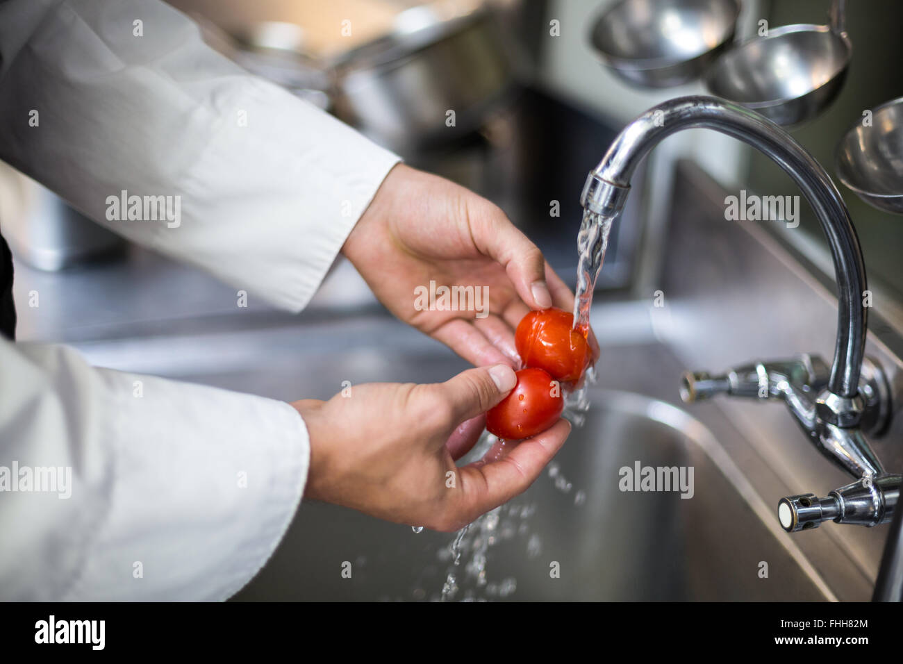 Chef washing cherry tomatoes under the tap Stock Photo - Alamy