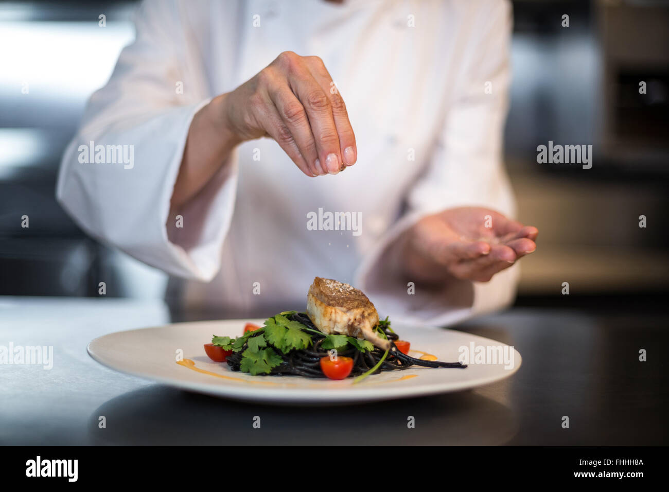 Chef seasoning her dish Stock Photo - Alamy