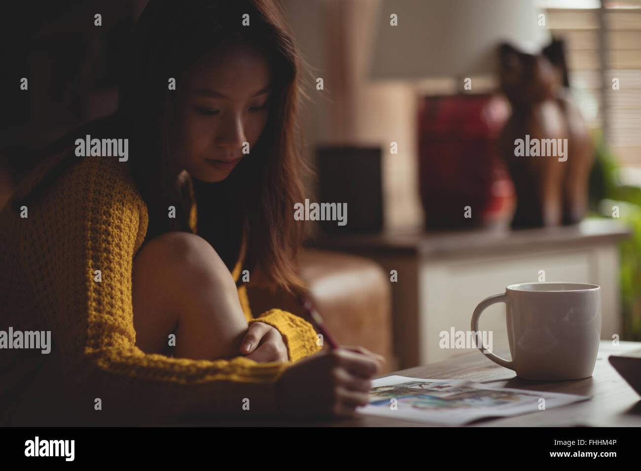 Brunette writing while drinking coffee Stock Photo - Alamy