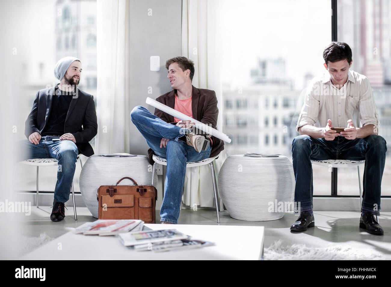 Three men sitting at the window in office Stock Photo - Alamy