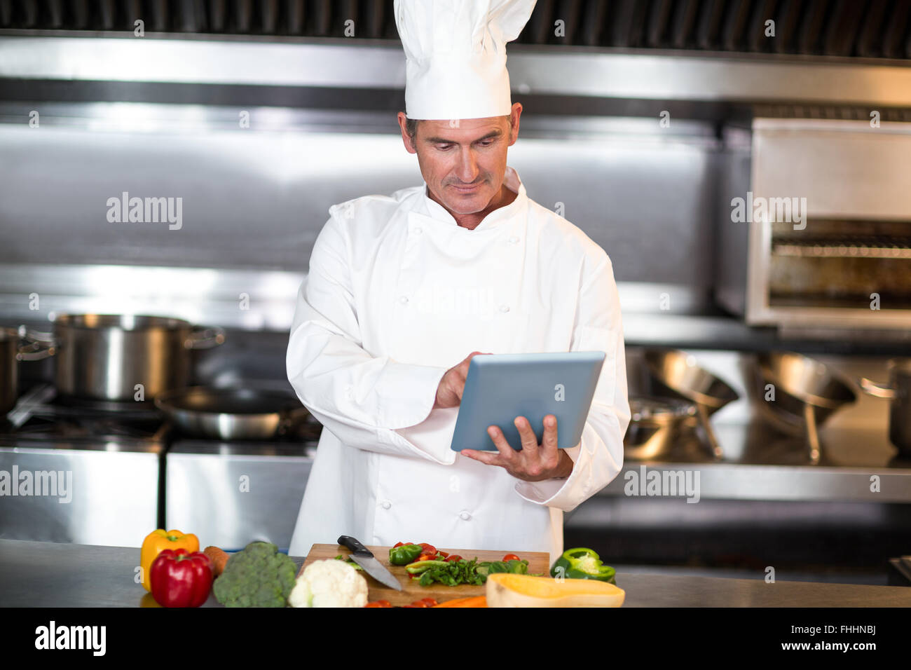 Chef preparing vegetables at counter with tablet Stock Photo - Alamy