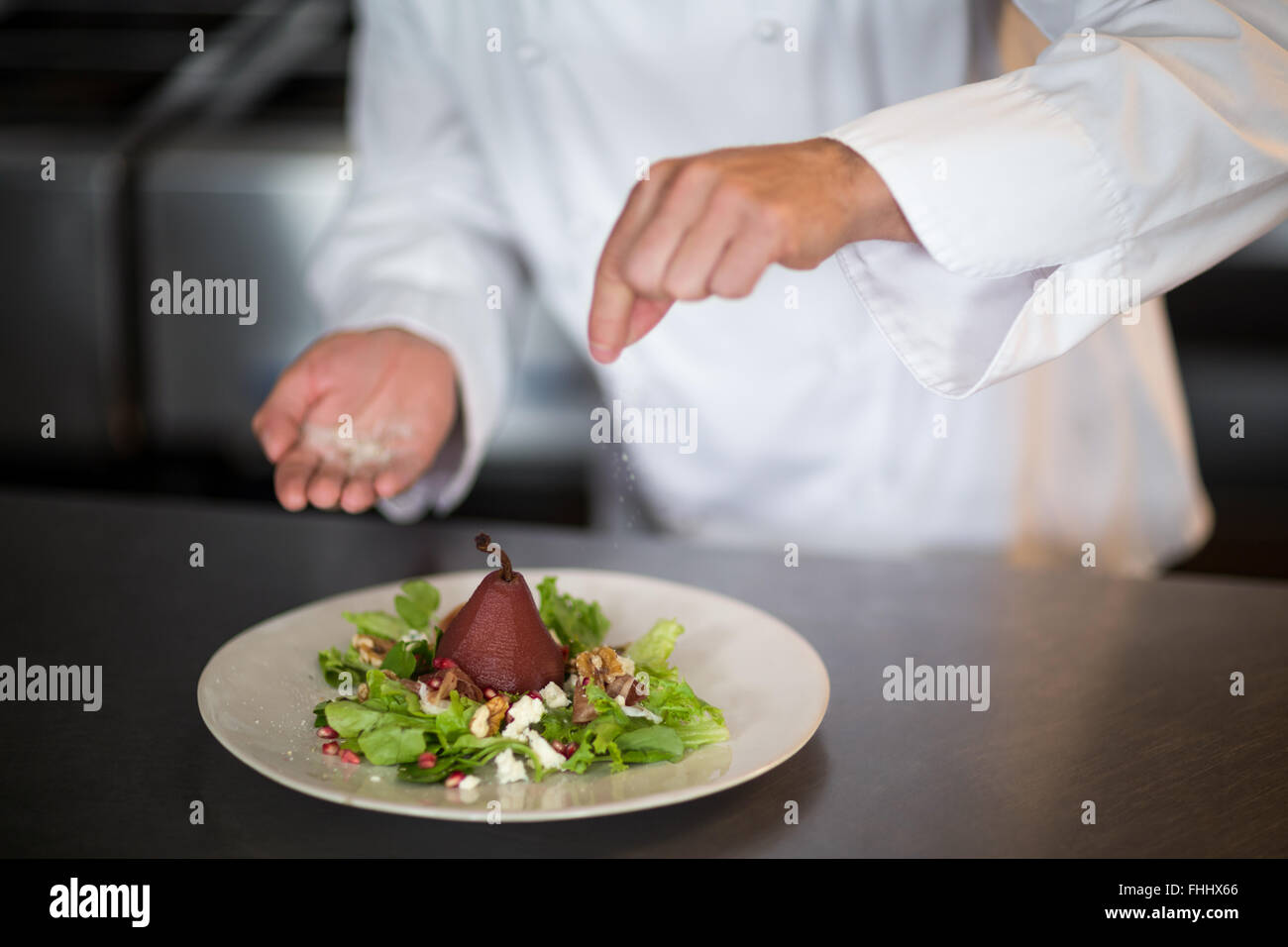 Chef seasoning salad on counter Stock Photo - Alamy