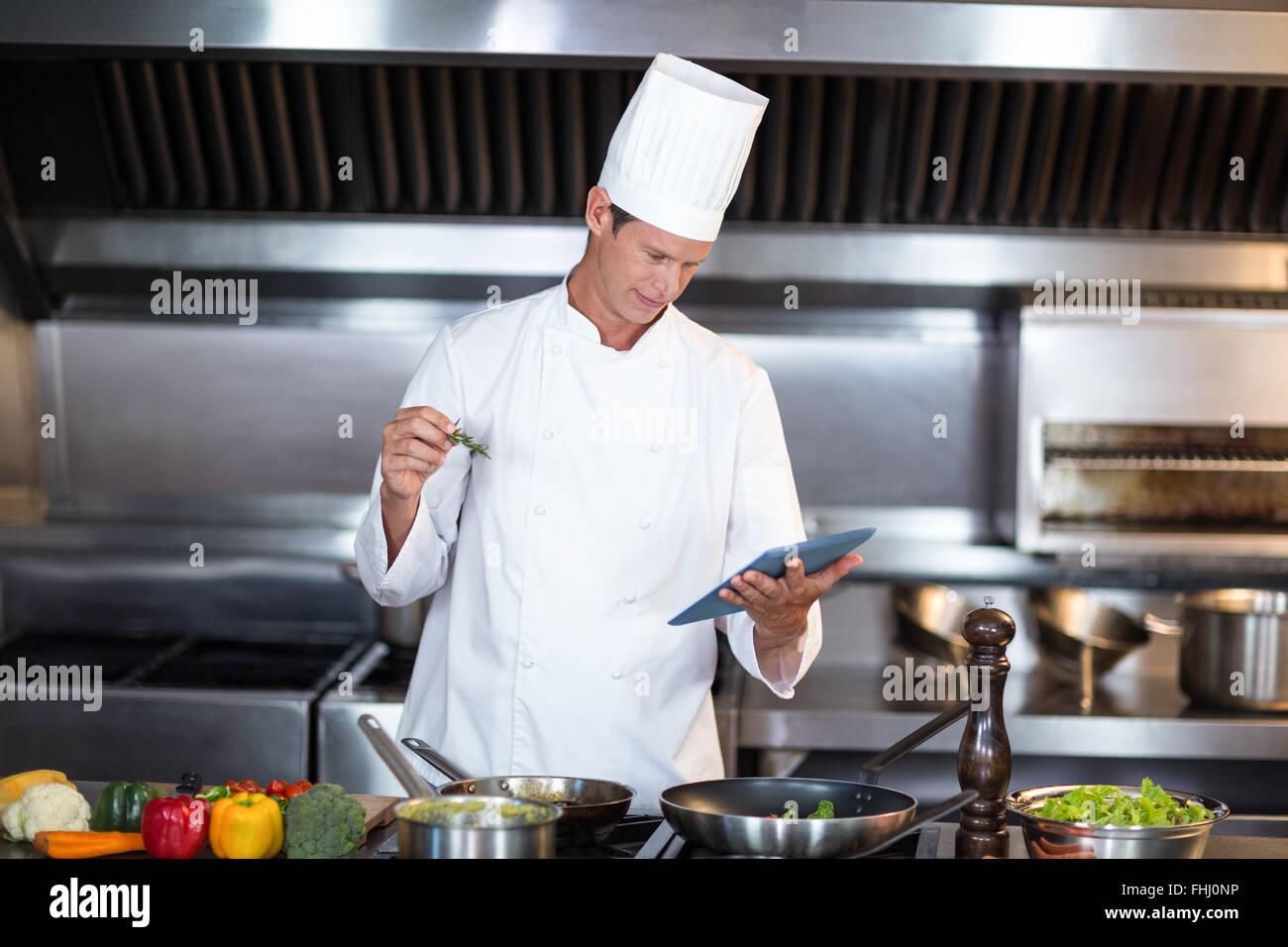 Happy chef using tablet pc while cooking Stock Photo - Alamy