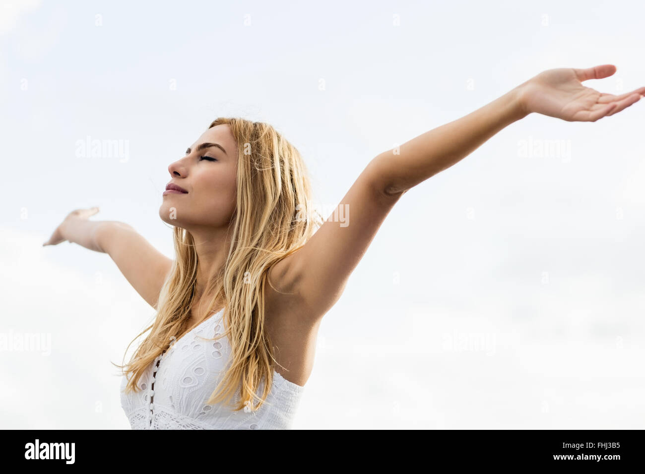 Beautiful blonde woman with arms outstretched Stock Photo - Alamy