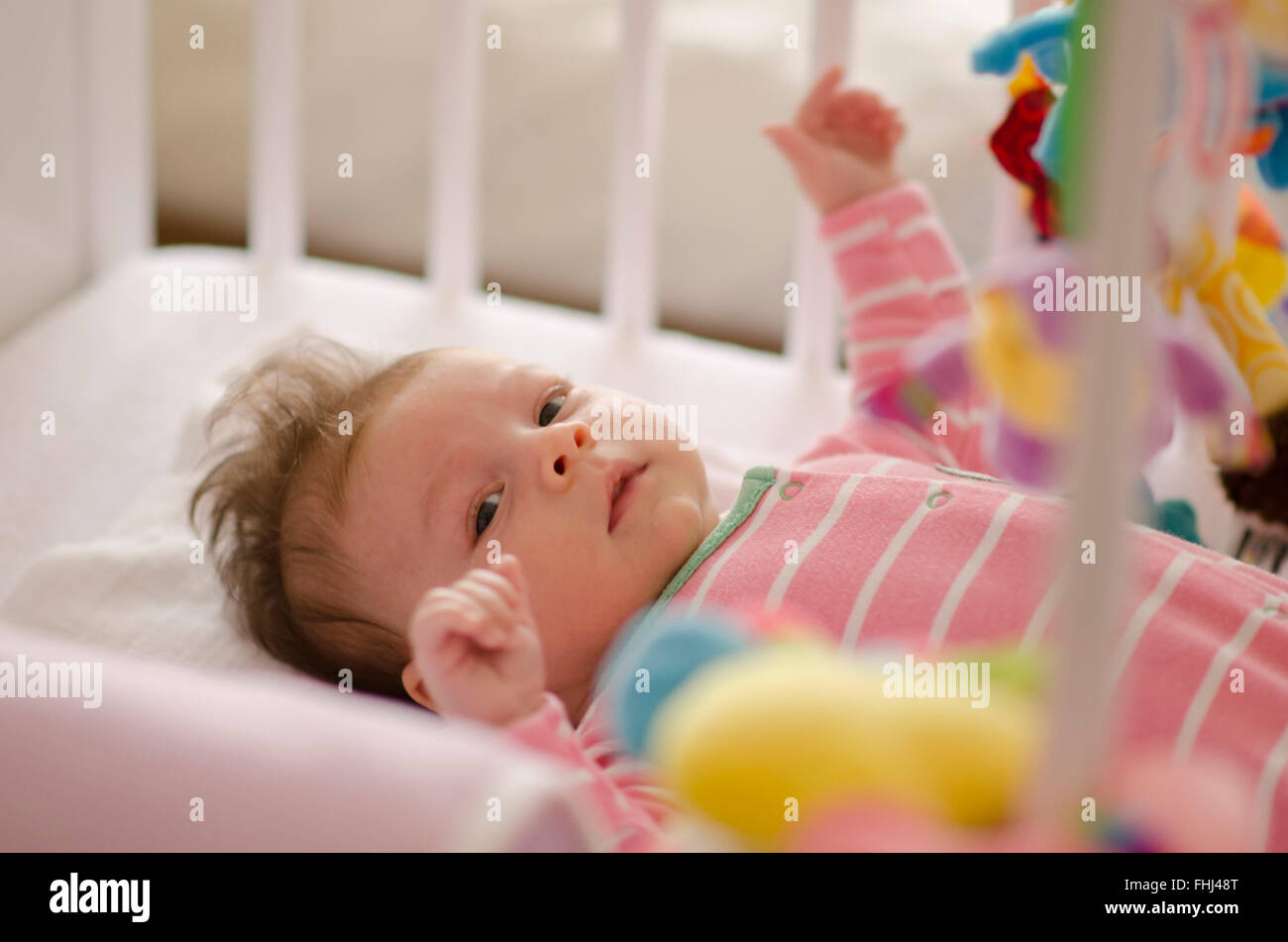 little cute baby girl playing in a cot Stock Photo - Alamy