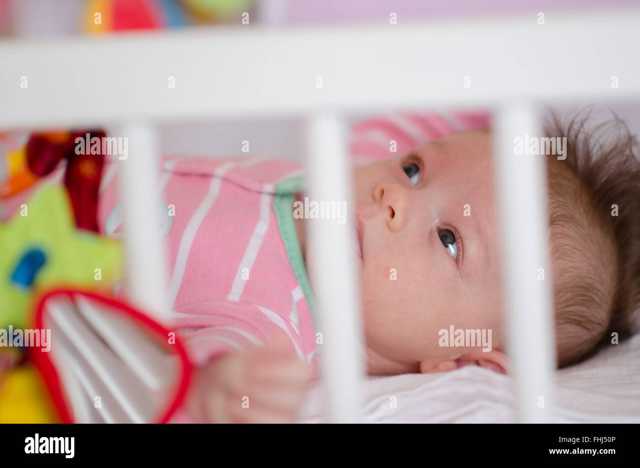 little cute baby girl playing in a cot Stock Photo - Alamy