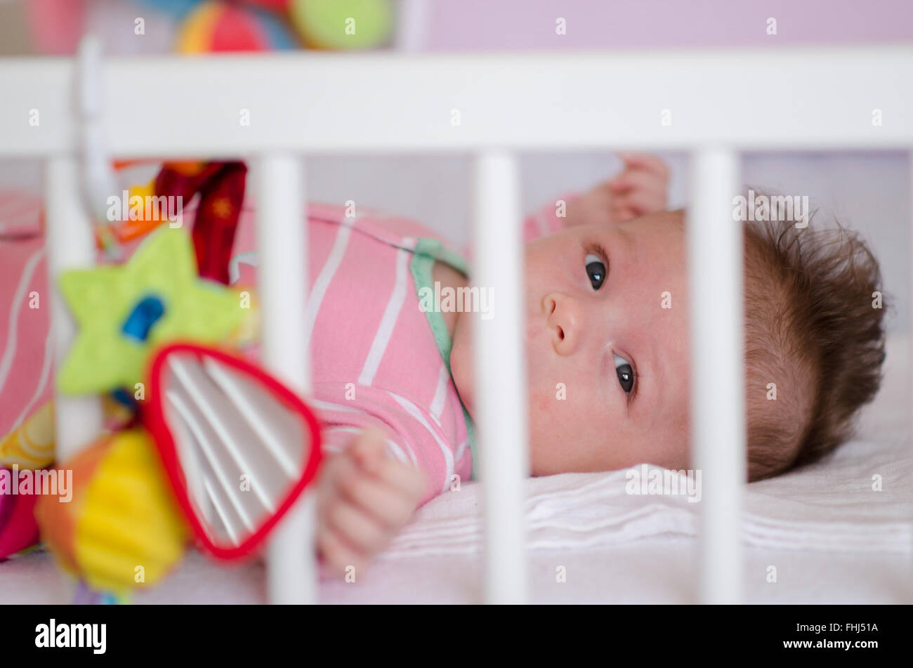 little cute baby girl playing in a cot Stock Photo - Alamy