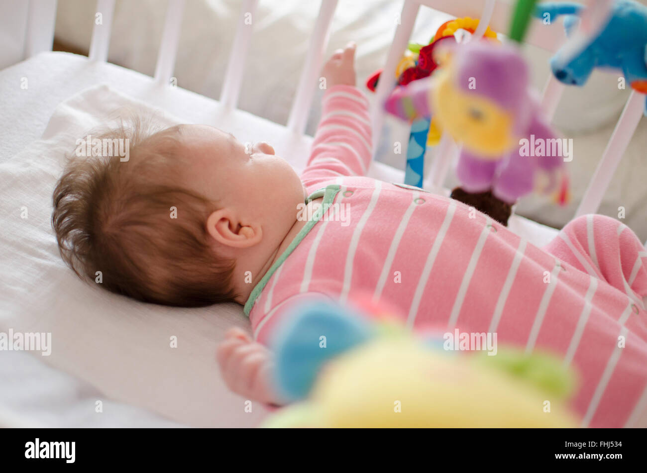 little cute baby girl playing in a cot Stock Photo - Alamy
