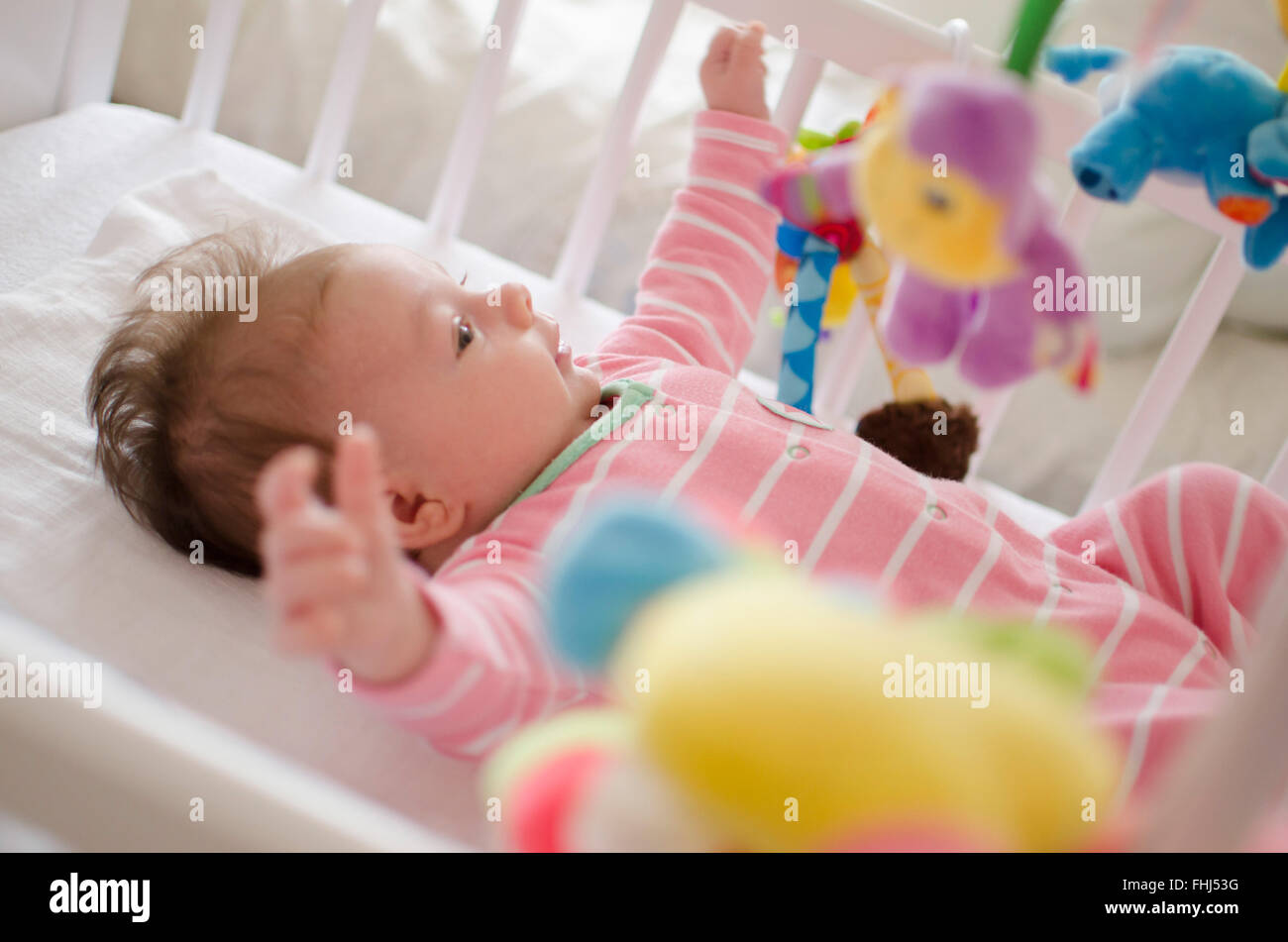 little cute baby girl playing in a cot Stock Photo - Alamy