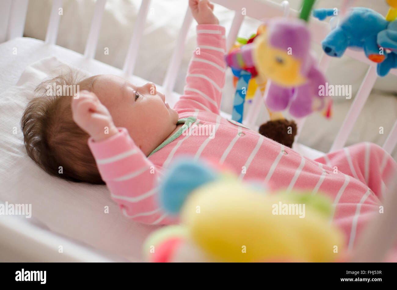 little cute baby girl playing in a cot Stock Photo - Alamy