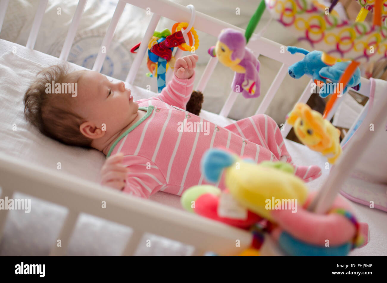 little cute baby girl playing in a cot Stock Photo - Alamy