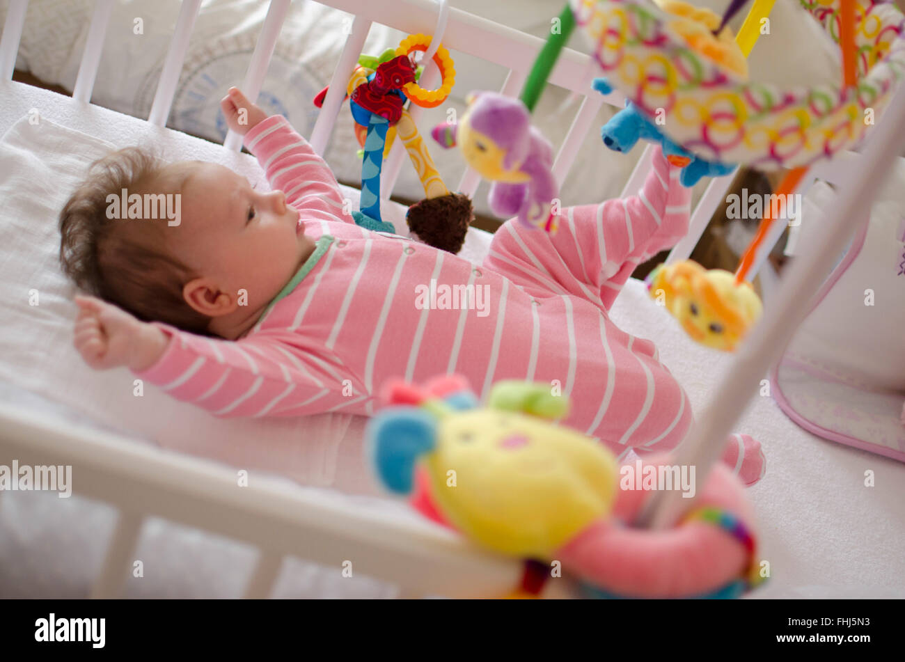 little cute baby girl playing in a cot Stock Photo - Alamy