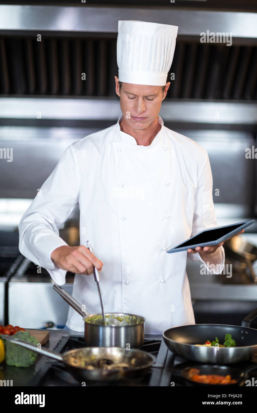 Happy chef using tablet pc while cooking Stock Photo - Alamy