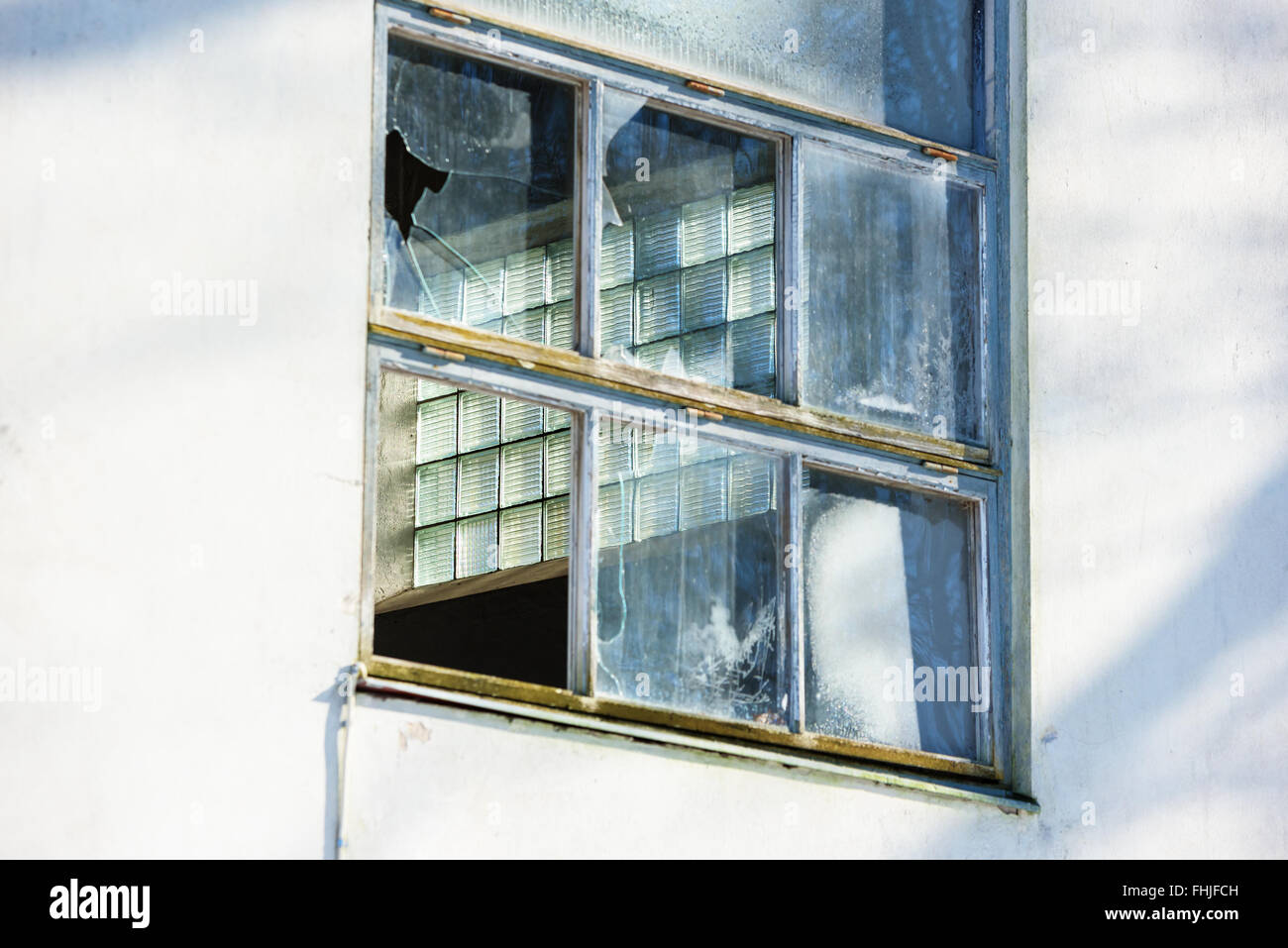 Behind a broken industrial window is yet another window with patterned ...