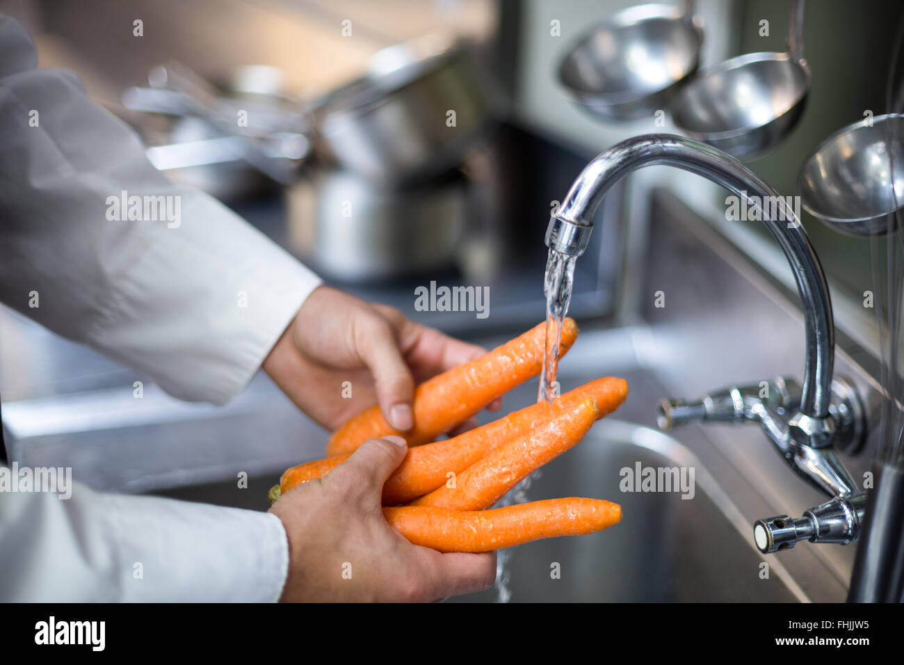 Chef washing carrots under the tap Stock Photo - Alamy