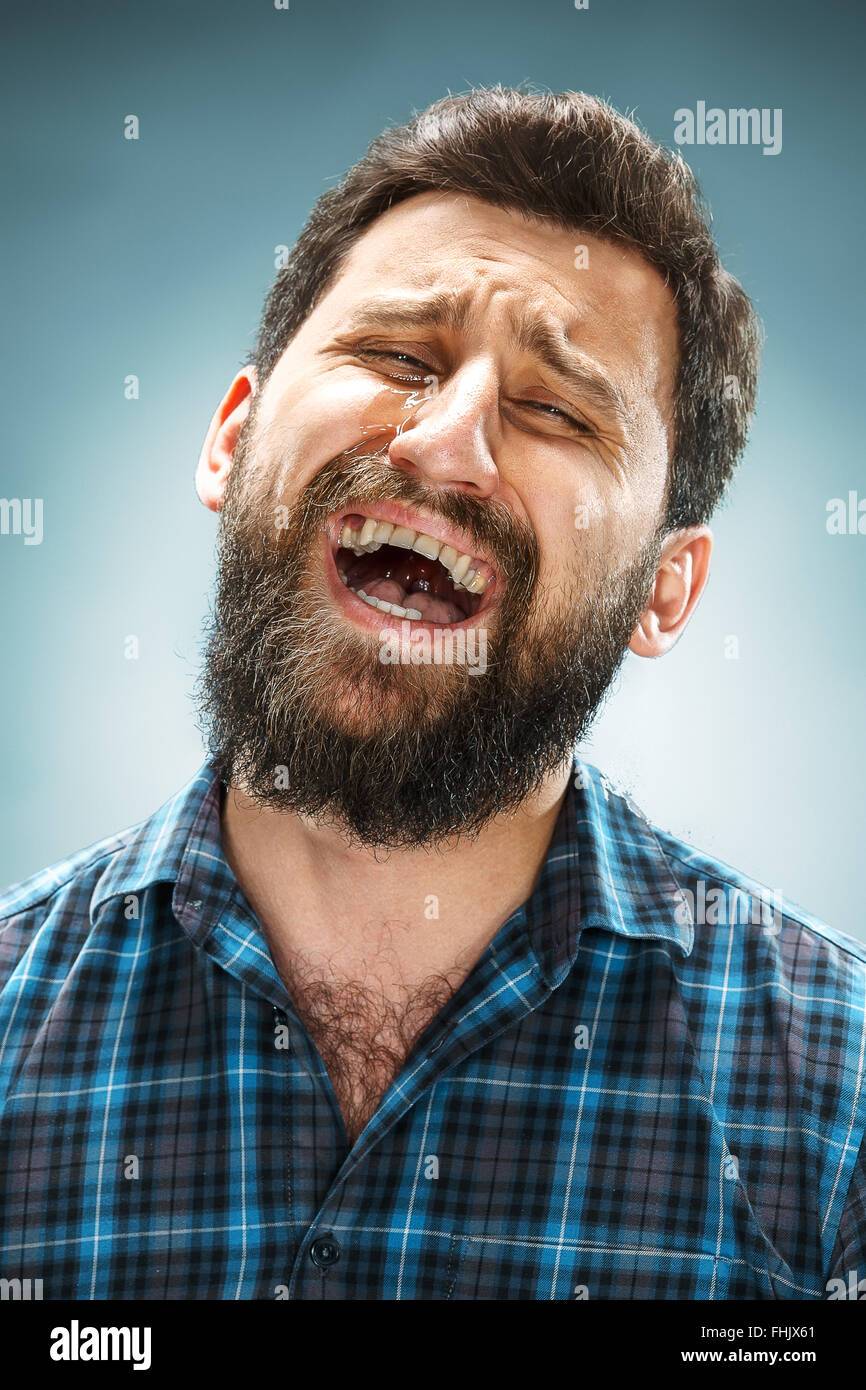 The crying man with tears on face closeup on blue background Stock ...