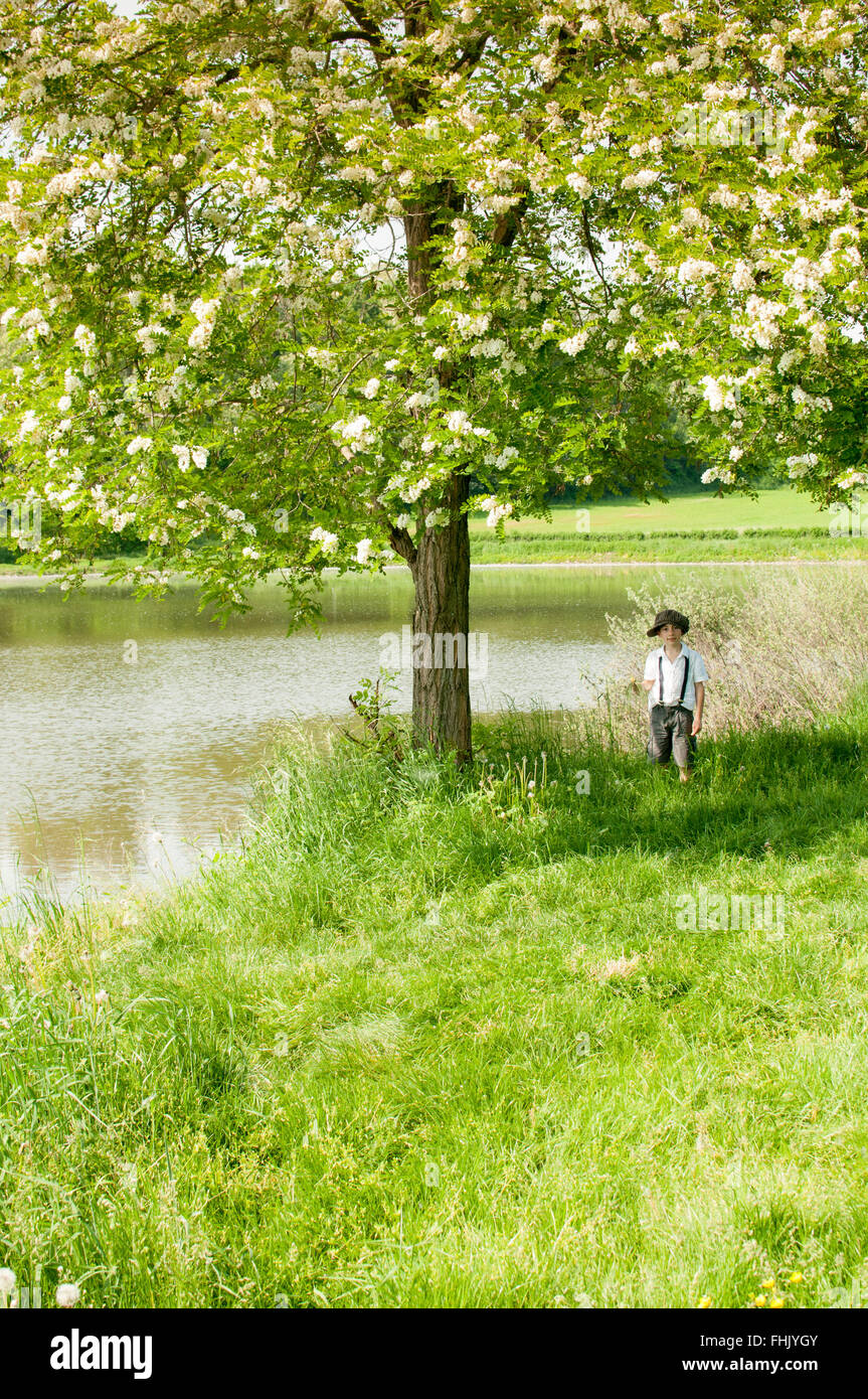 Italy, little boy wearing vintage clothing standing under a tree Stock ...