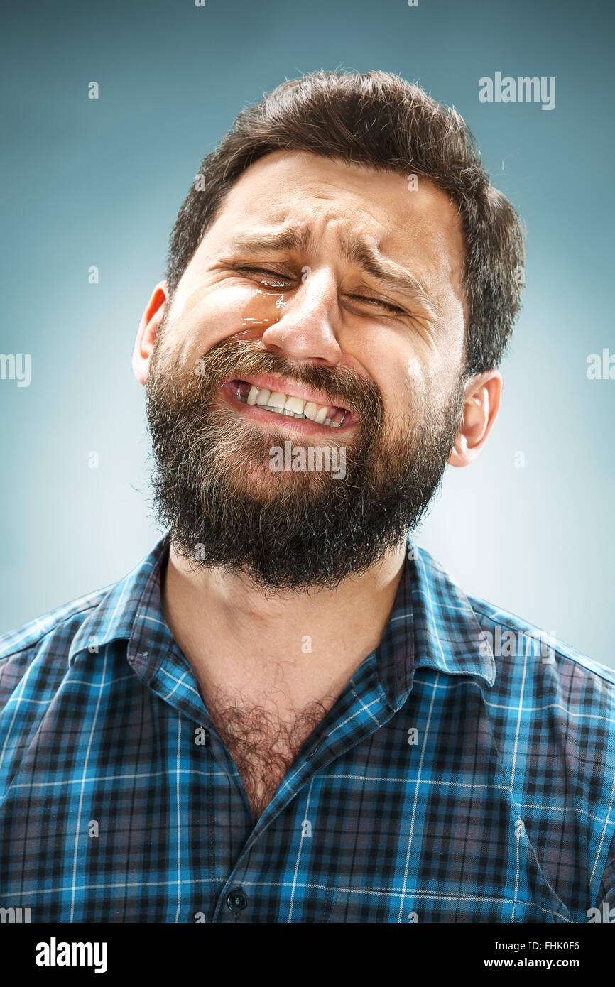 The crying man with tears on face closeup on blue background Stock ...