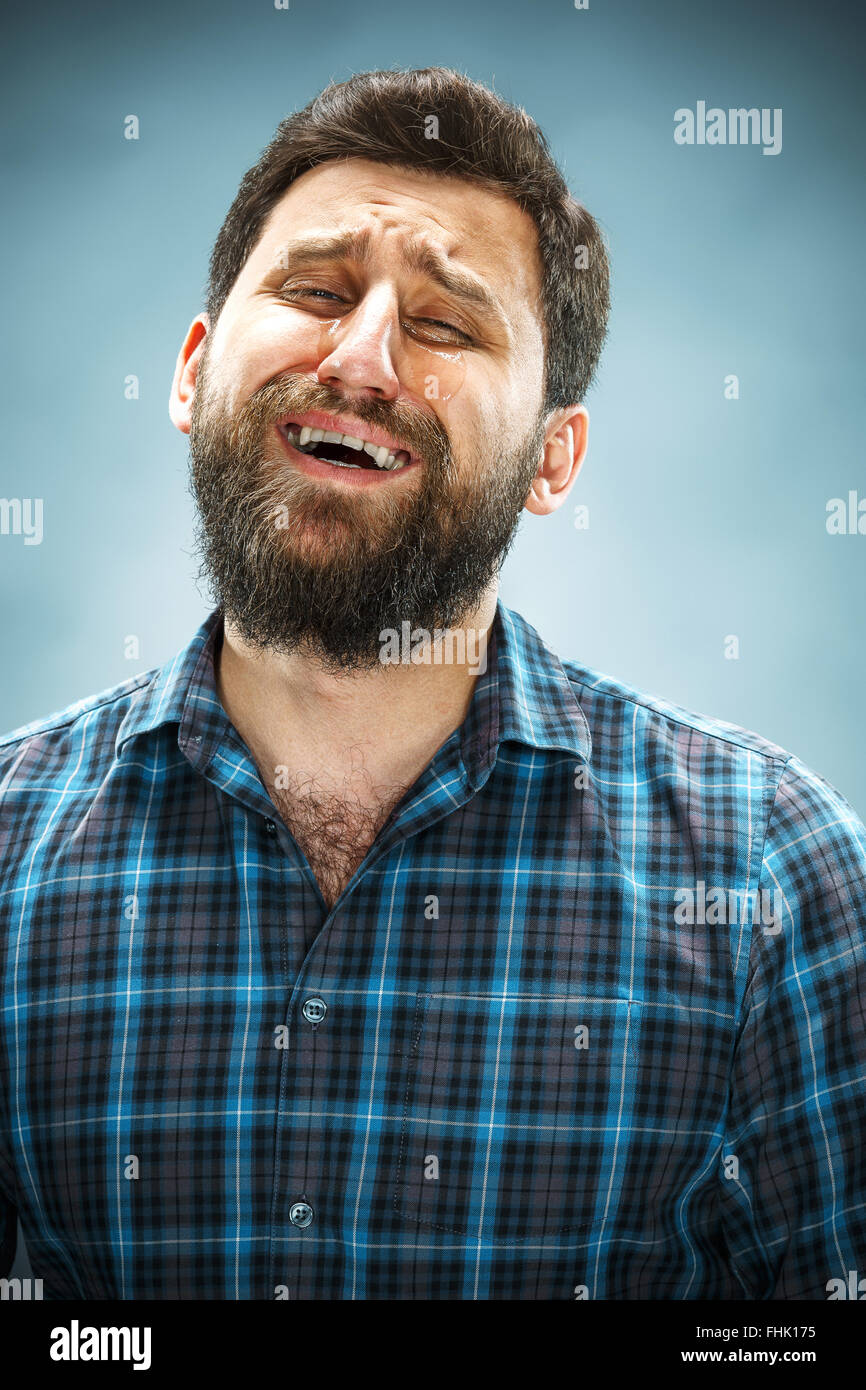 The crying man with tears on face closeup on blue background Stock ...