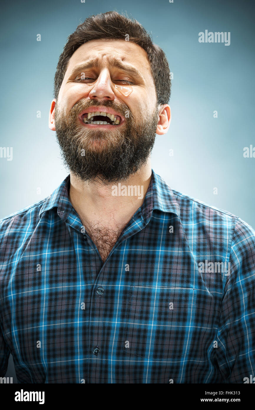The crying man with tears on face closeup on blue background Stock ...