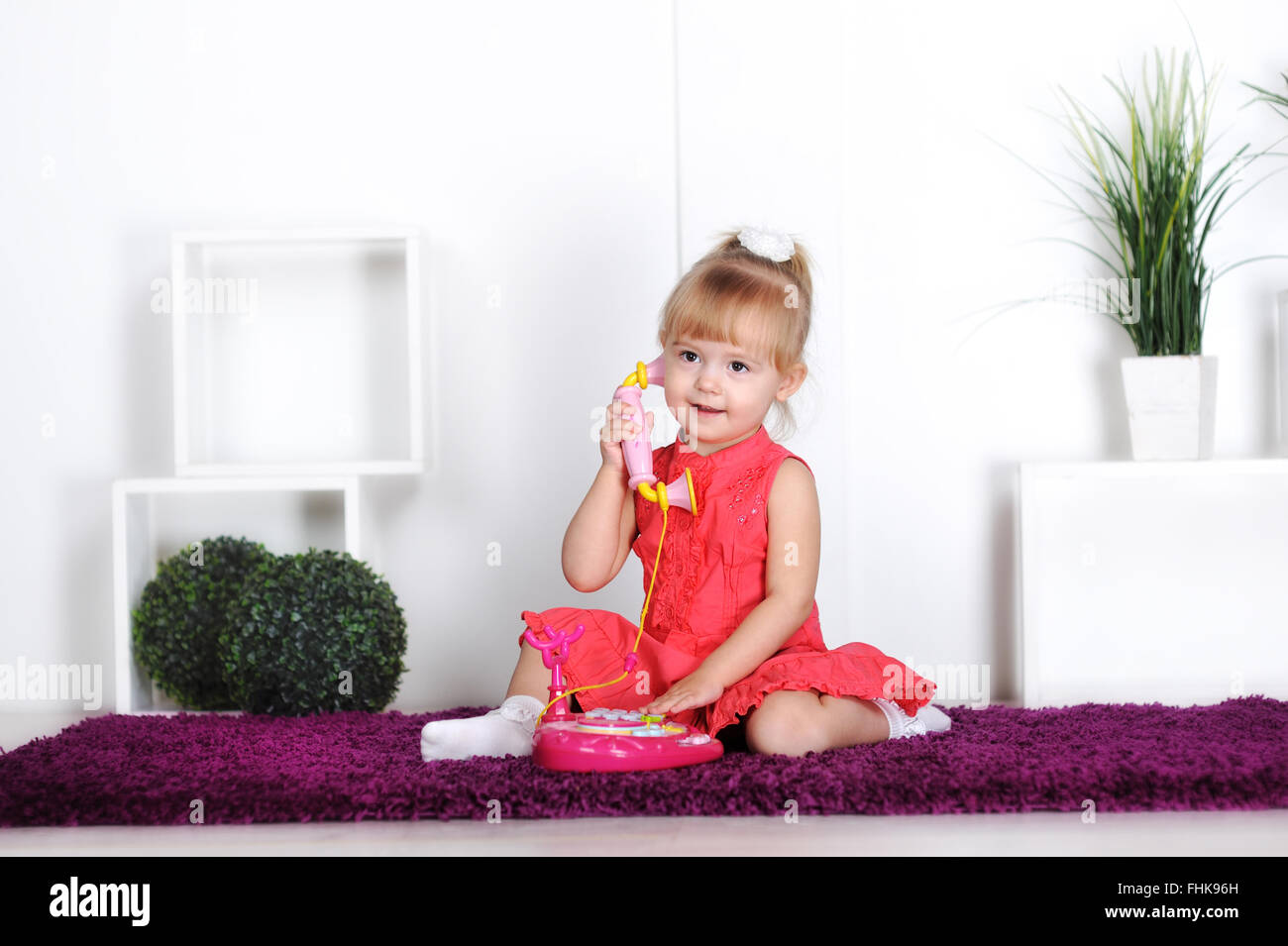 Blonde girl, wearing a dress, talking on the toy phone, calling Stock ...