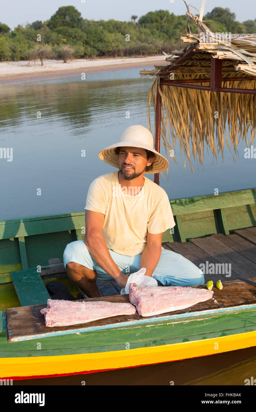 Fisherman preparing a surubim catfish on the beach in Alter do Chao ...