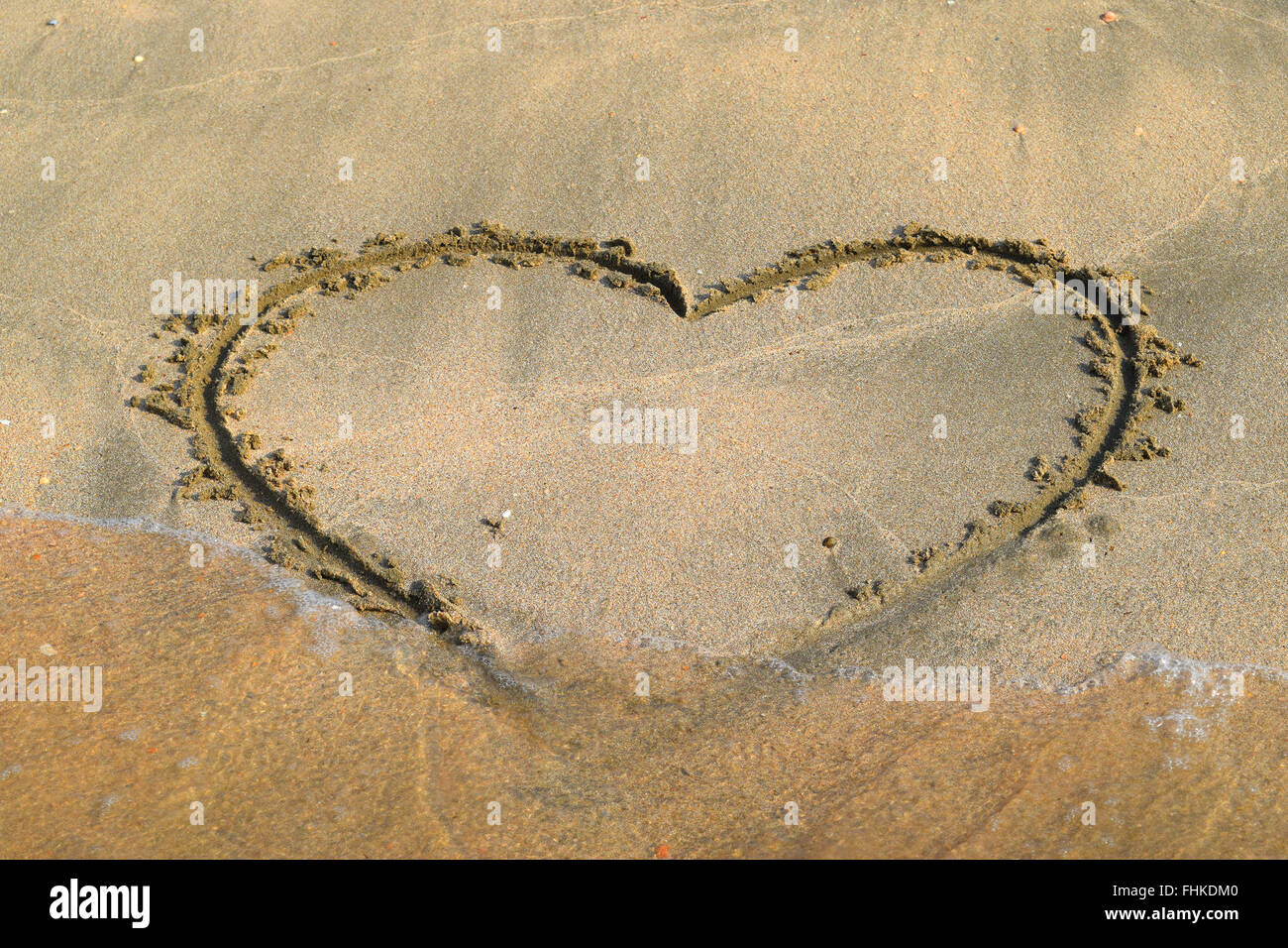 Heart drawn on the beach sand. heart symbol on the sand washed by the ...