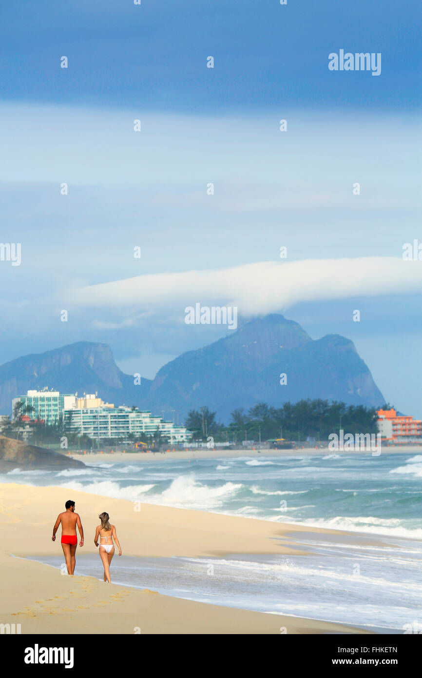 A young Brazilian couple walking along Praia do Pontal beach, Recreio ...