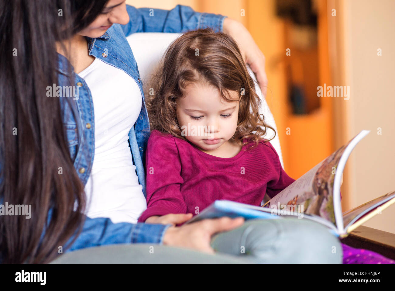 Portrait of little girl watching children's book with her mother Stock ...