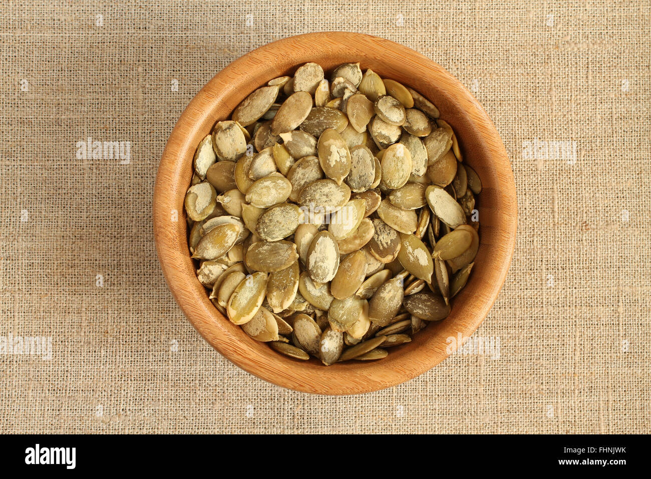 Shelled pumpkin seeds in bamboo bowl on rough linen cloth Stock Photo ...