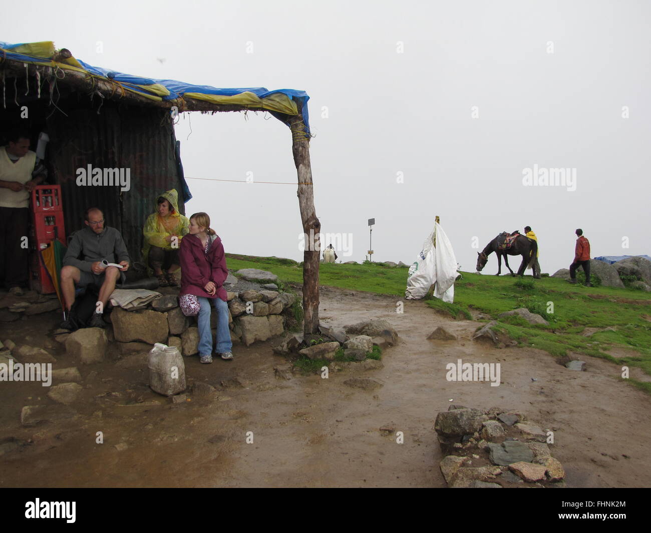 Tourists seek shelter from the rain under a tarp hut at Triund Stock ...